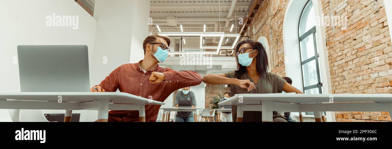 Students siting and greeting bumping elbows at workplace Stock Photo ...