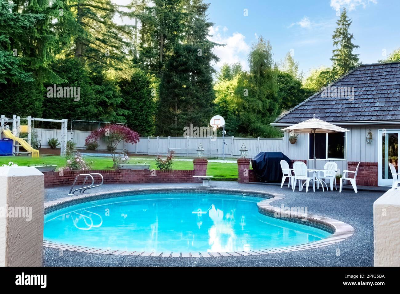 Heart shaped home swimming pool in large backyard during summer time ...