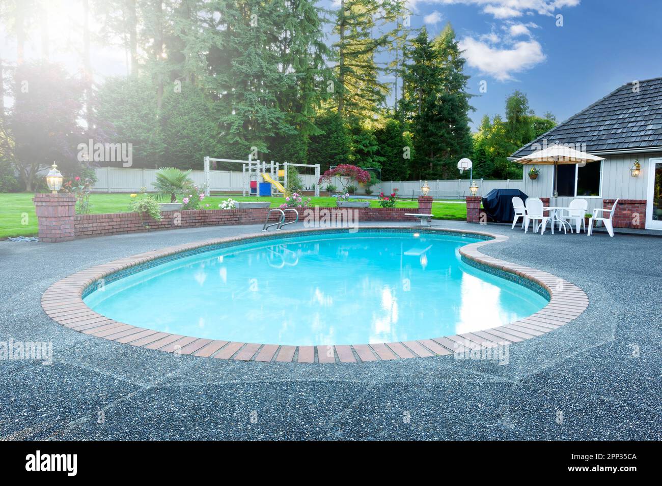 Heart shaped home swimming pool in large backyard during late daylight ...