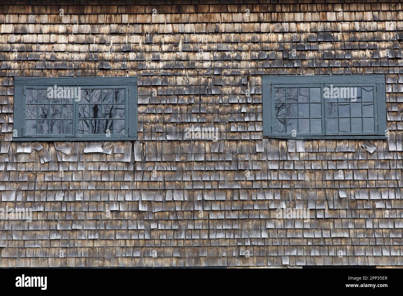 Old Rhode Island barn with wooden shingles and two window with green ...