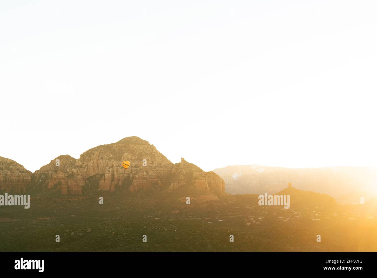 Hot air balloon floating in the early morning sun rays of Sedona ...