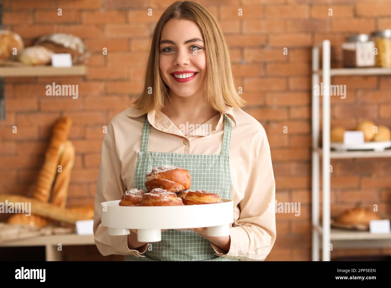 Female baker with tray of tasty buns in kitchen Stock Photo - Alamy