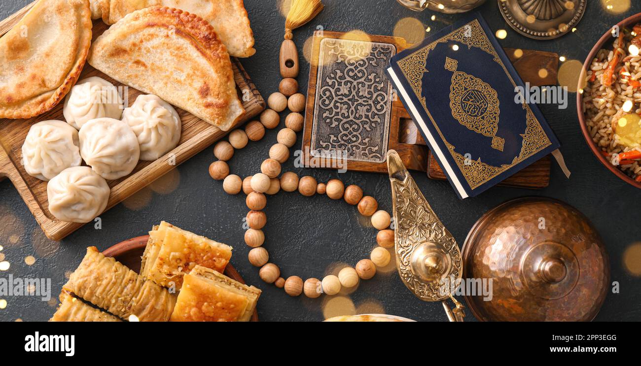 Traditional Eastern dishes with Quran, Aladdin lamp and tasbih on dark ...