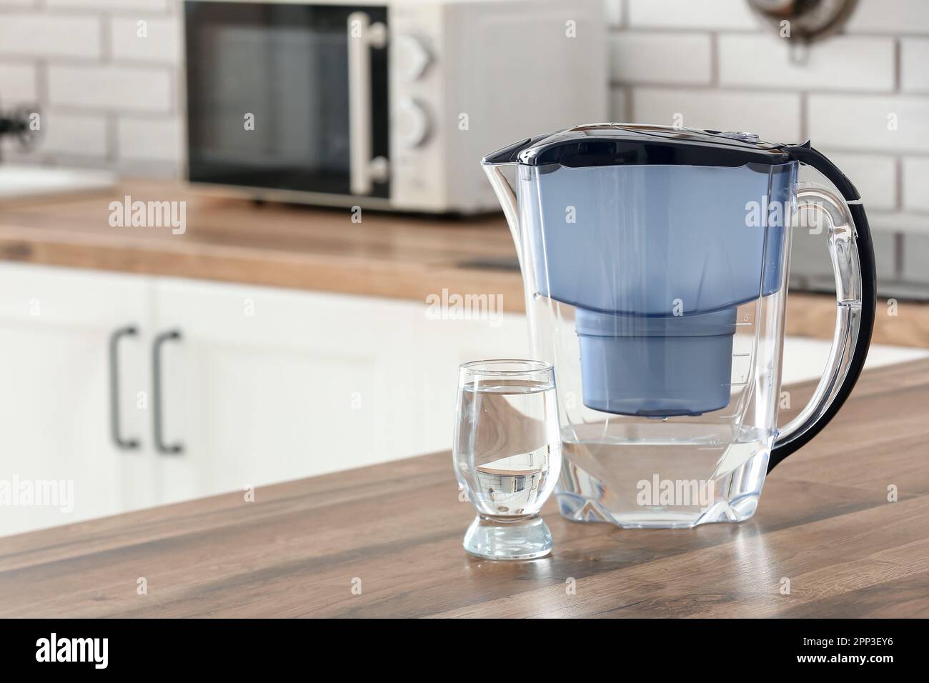 Modern filter jug and glass of water on kitchen counter Stock Photo - Alamy