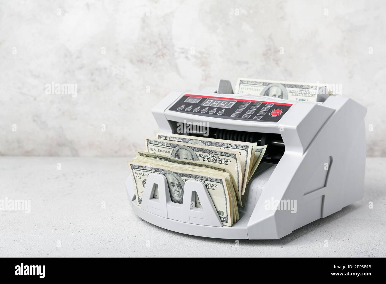Modern cash counting machine with dollar banknotes on light background ...