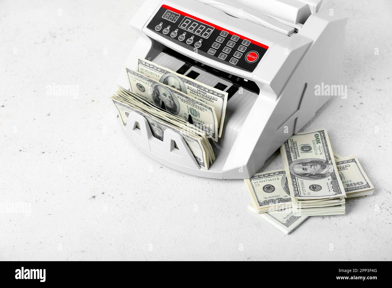 Modern cash counting machine with dollar banknotes on light background ...