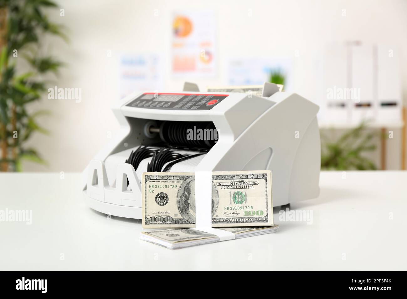 Modern cash counting machine with dollar banknotes on table in office ...
