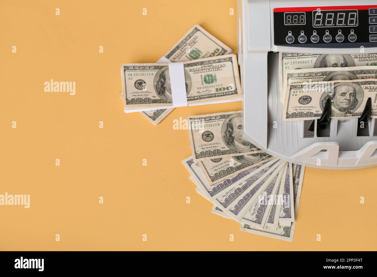 Modern cash counting machine with dollar banknotes on yellow background ...