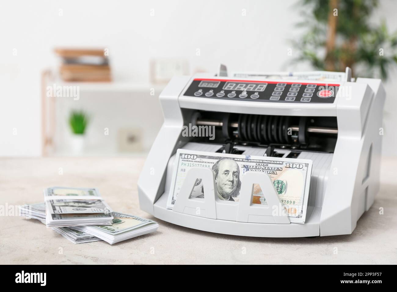 Modern cash counting machine with dollar banknotes on table in room ...