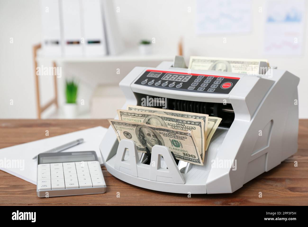 Modern cash counting machine with dollar banknotes and calculator on ...