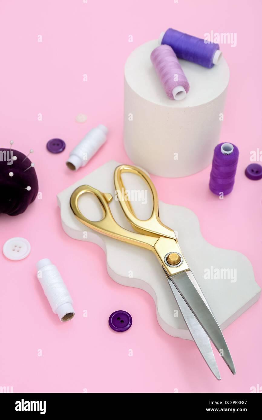 Podiums with scissors, buttons and thread spools on pink background ...