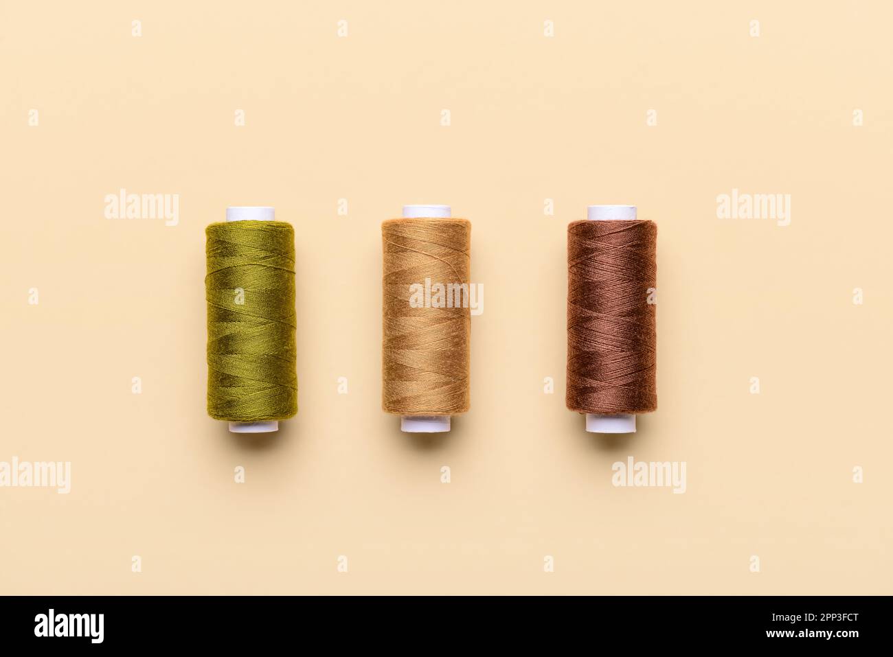 Three thread spools on color background Stock Photo - Alamy