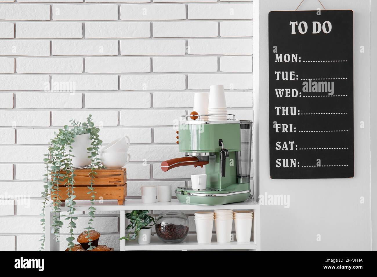 Modern coffee machine with cups and houseplants on shelving unit near ...