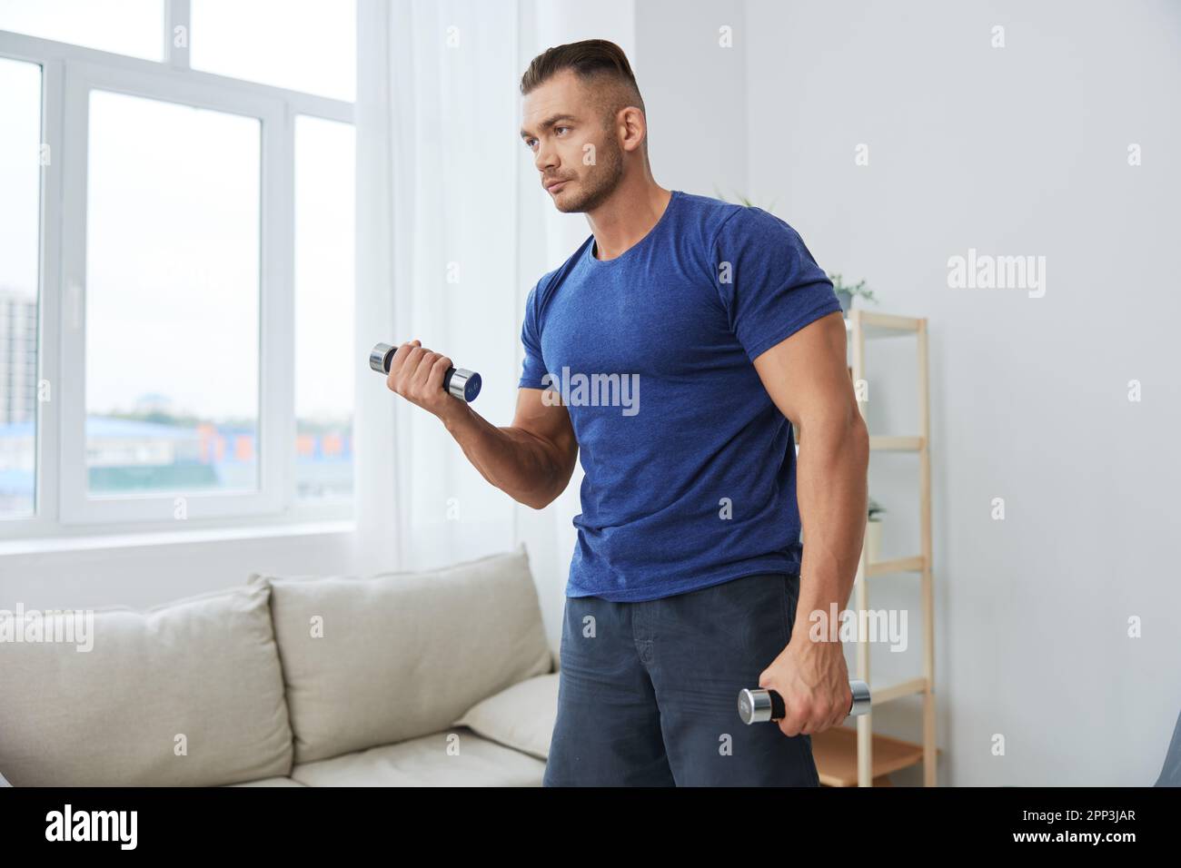 Man sportsman training at home with dumbbells, exercises for arms and ...