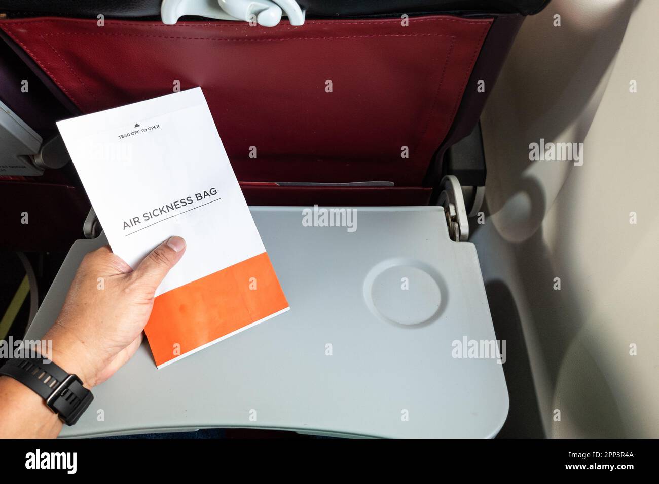 Passanger holding air sickness bag during air flight incase need to ...