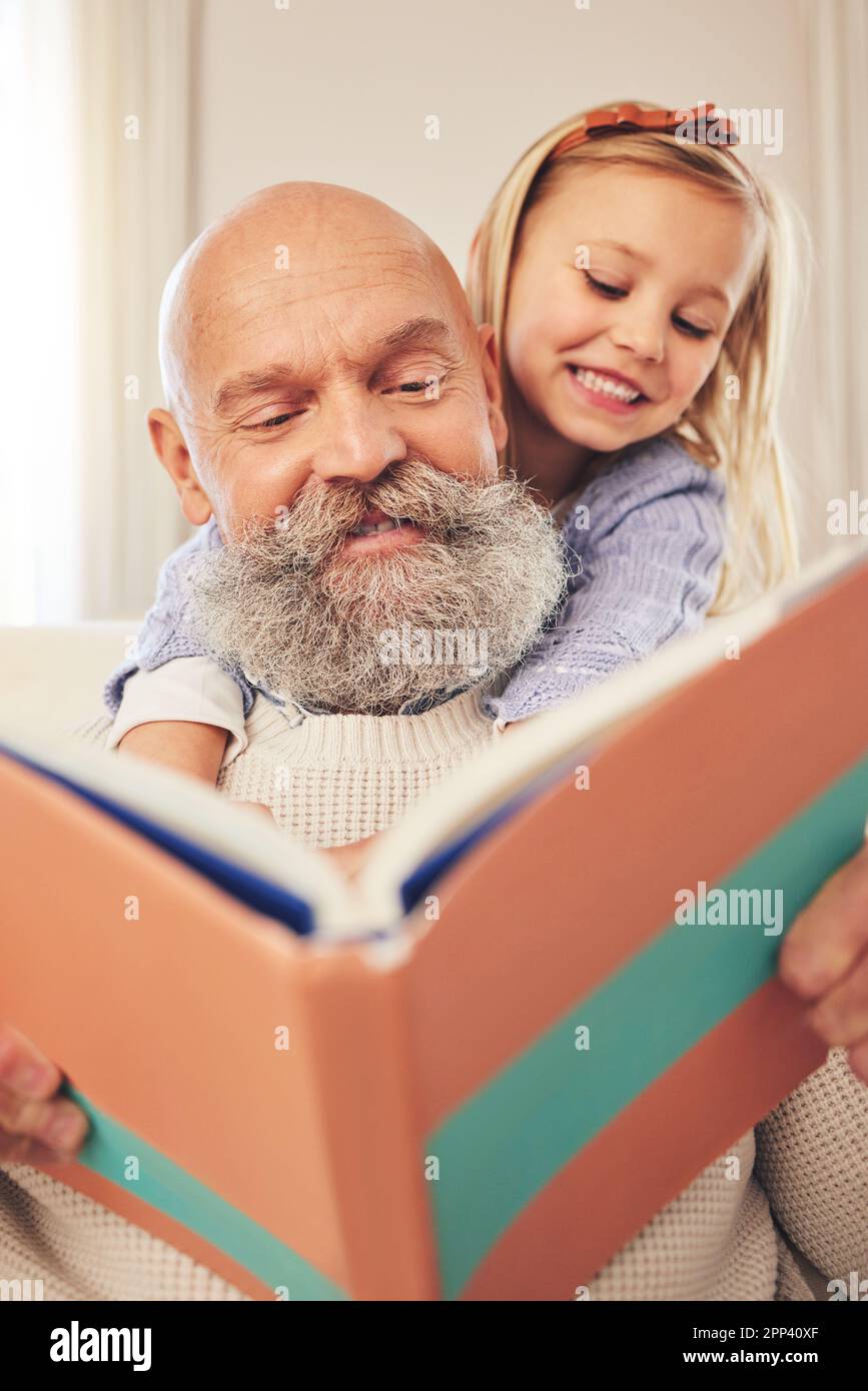 Grandfather, child and reading a story book in a family home for fun ...