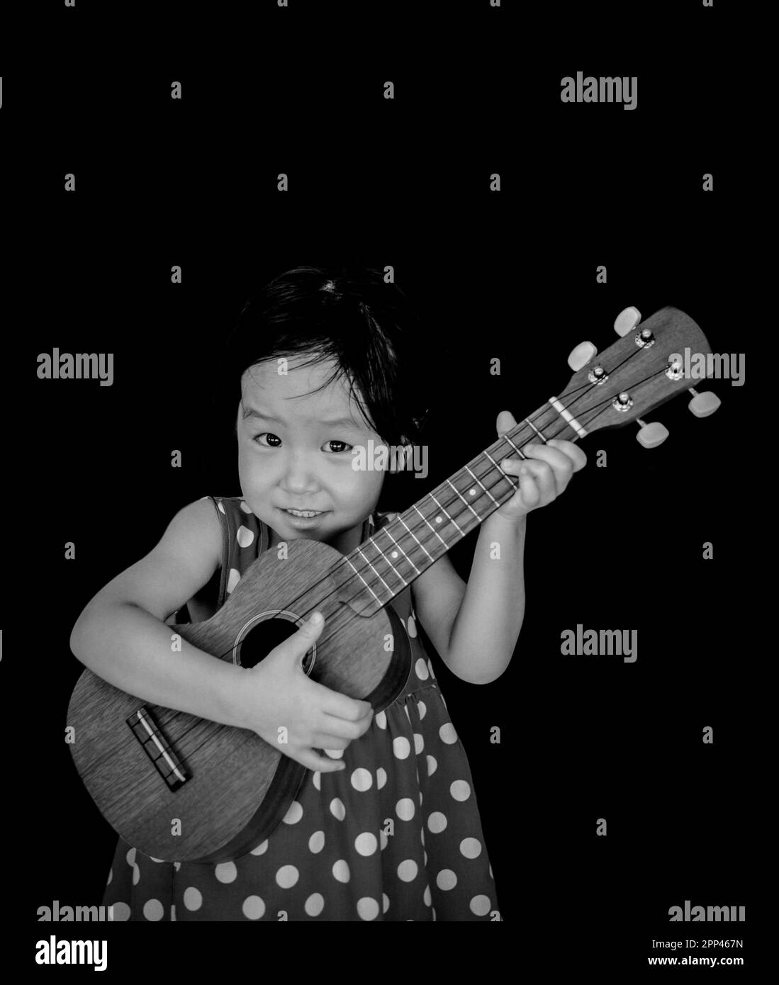 Little asian child play the ukulele Stock Photo - Alamy