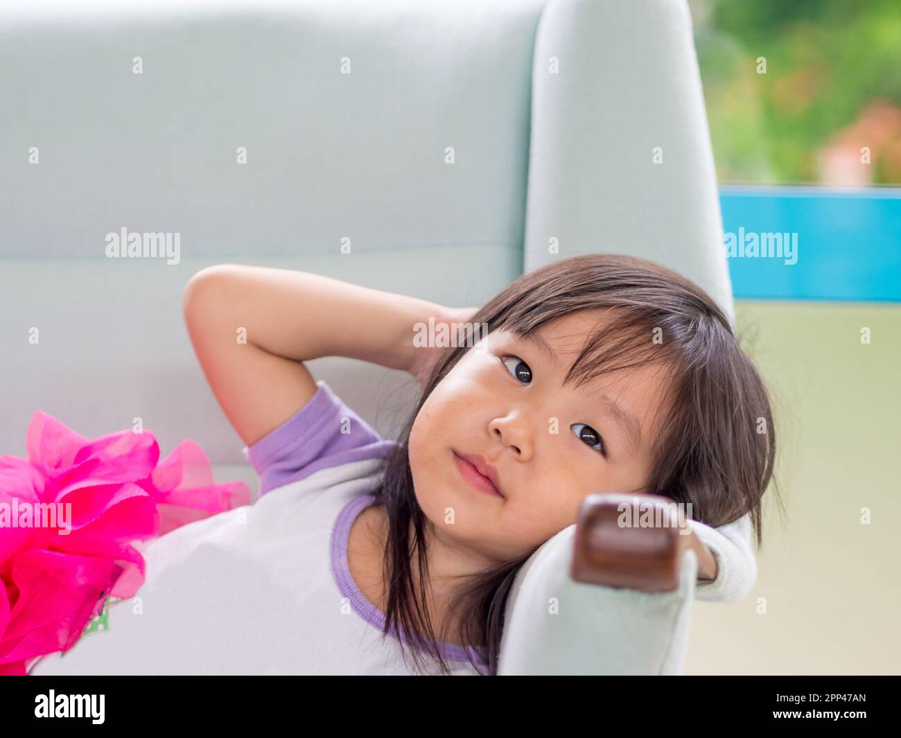 Beautiful young girl child laying down on a white sofa at home, asian ...