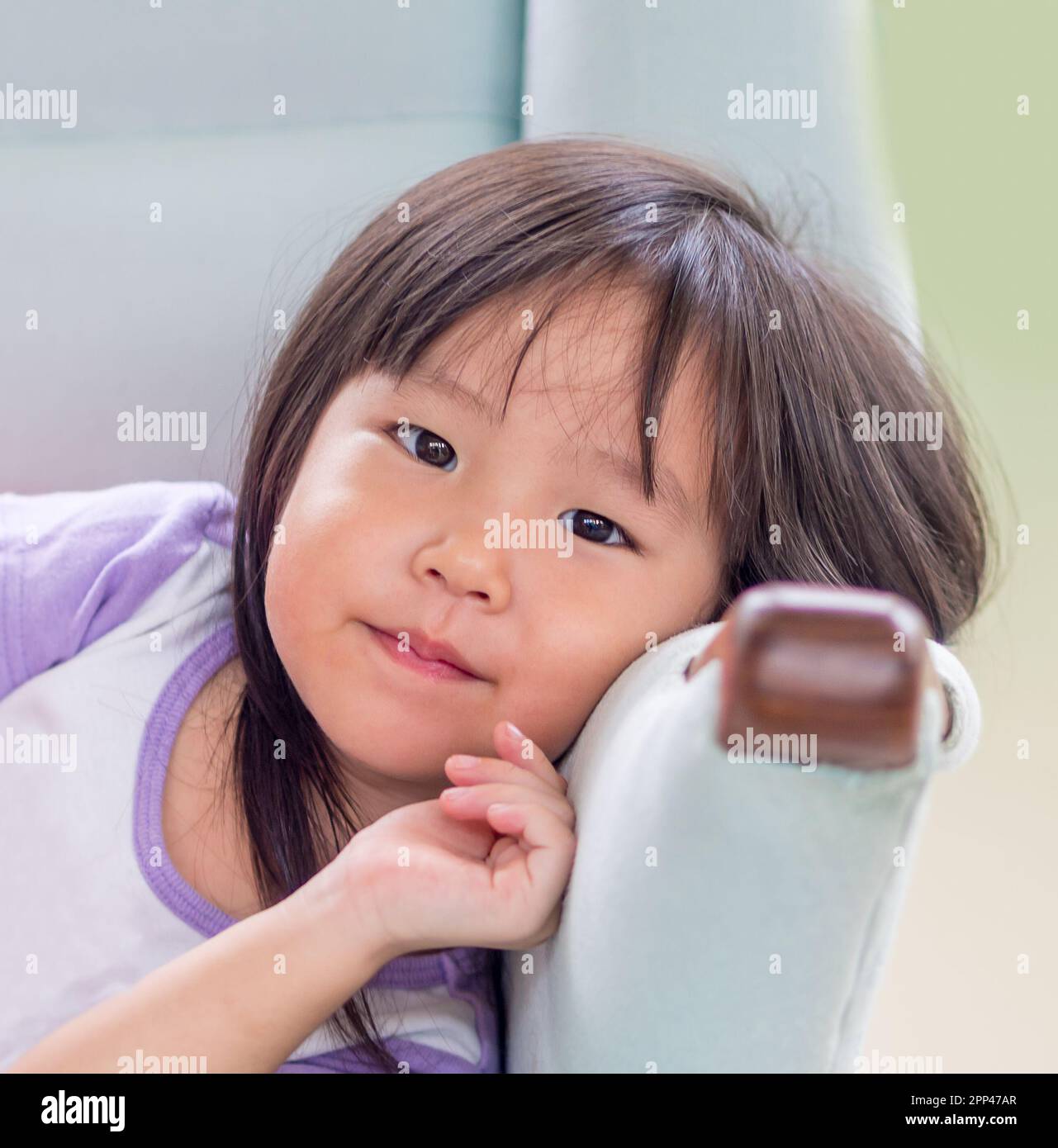 Beautiful young girl child laying down on a white sofa at home, asian ...