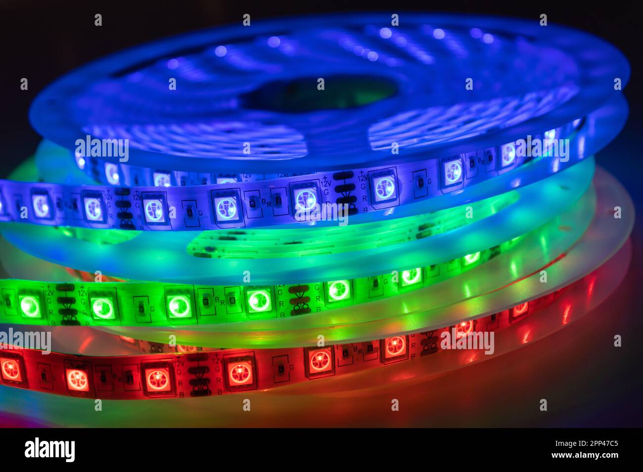 Bobbin with roll of glowing LED strip lighting placed on table, green ...