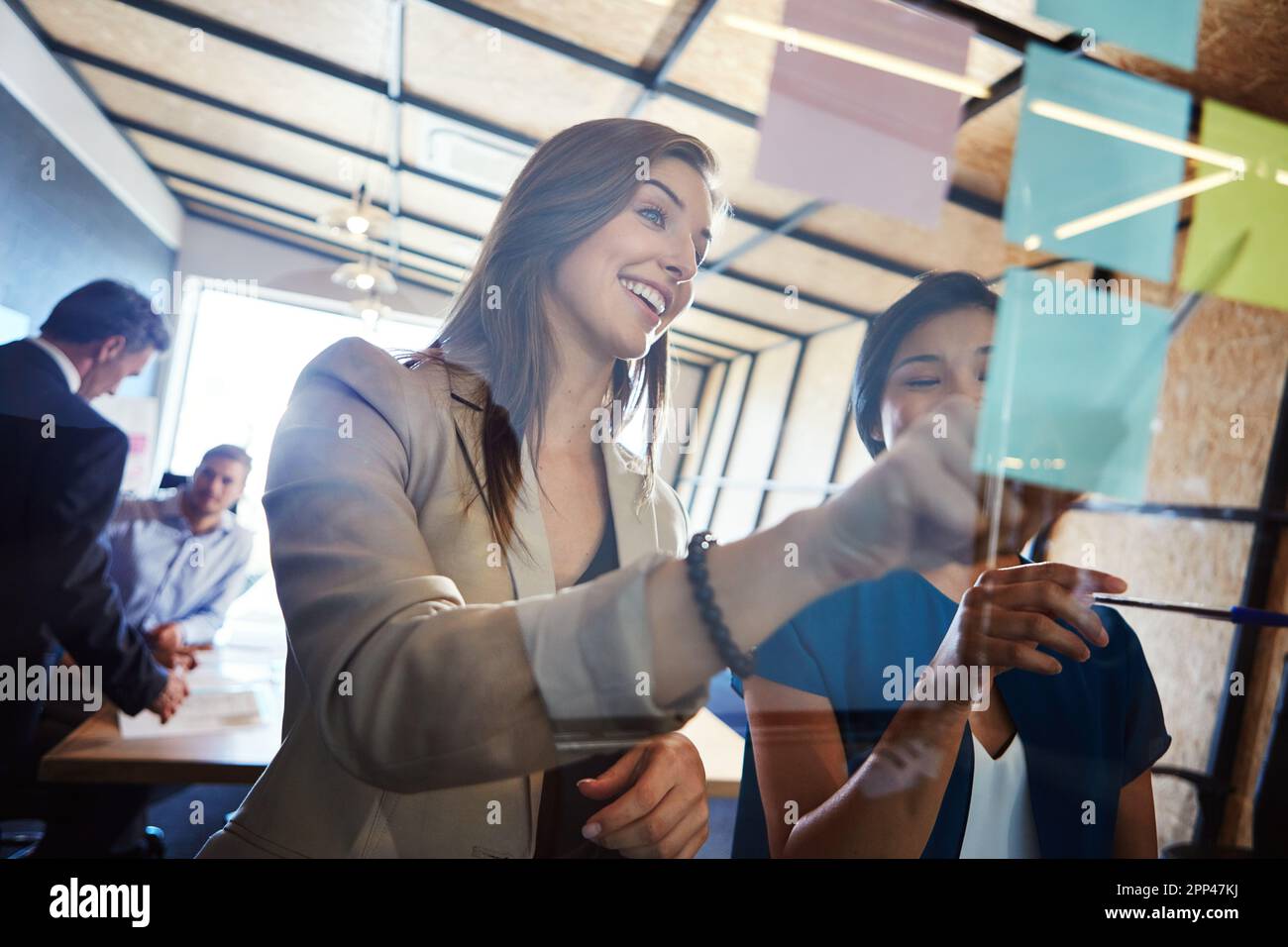 Prioritizing tasks for their project. coworkers arranging sticky notes ...