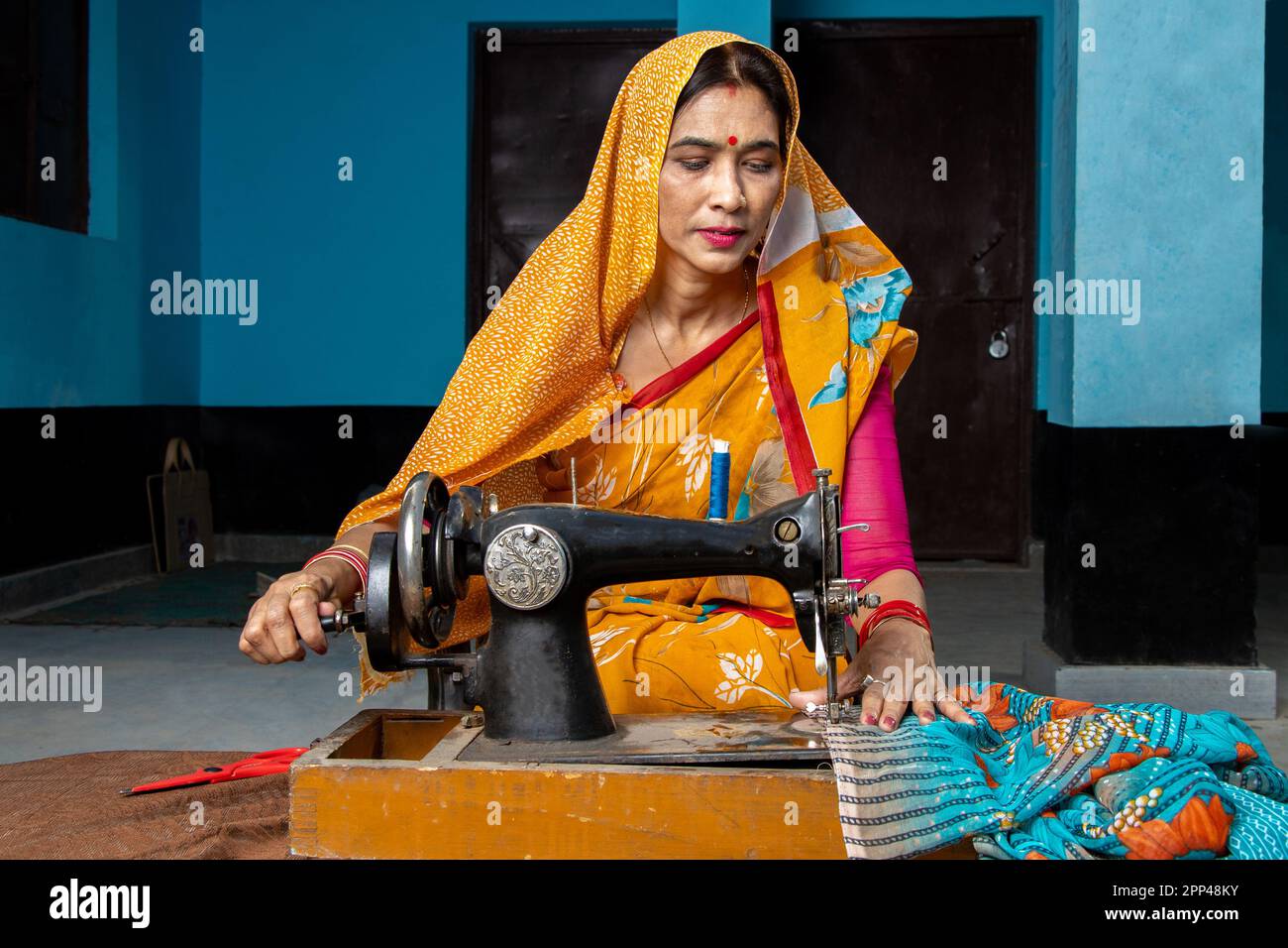 Traditional indian woman housewife wearing sari using sewing machine at ...