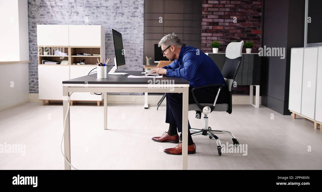 Bad Posture Sitting In Office Chair At Computer Desk Stock Photo - Alamy