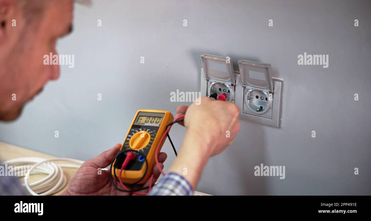 Male Electrician Checking Voltage Of Socket With Multimeter In House ...