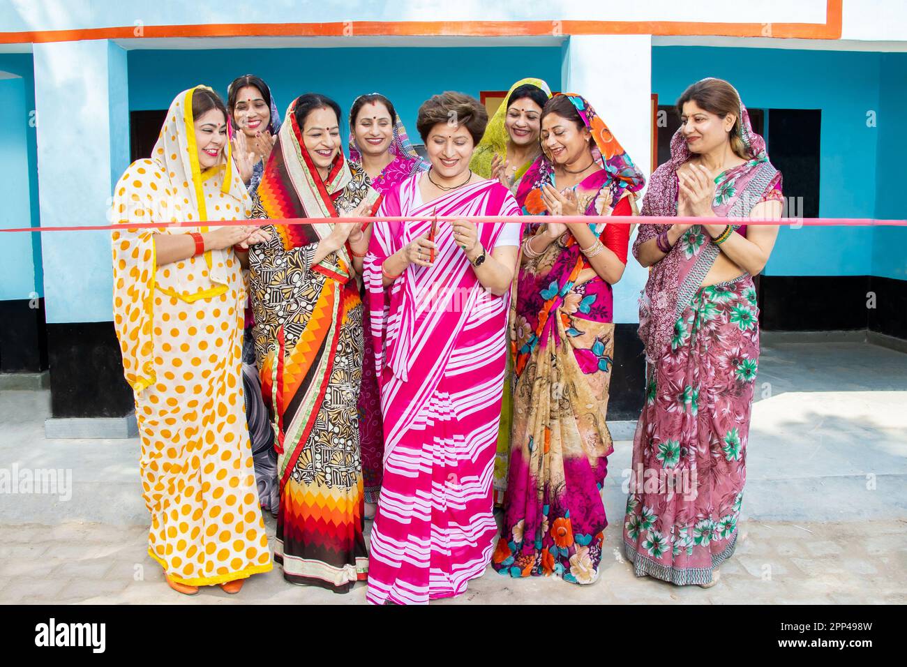Indian business woman in sari cutting red ribbon while colleagues are ...