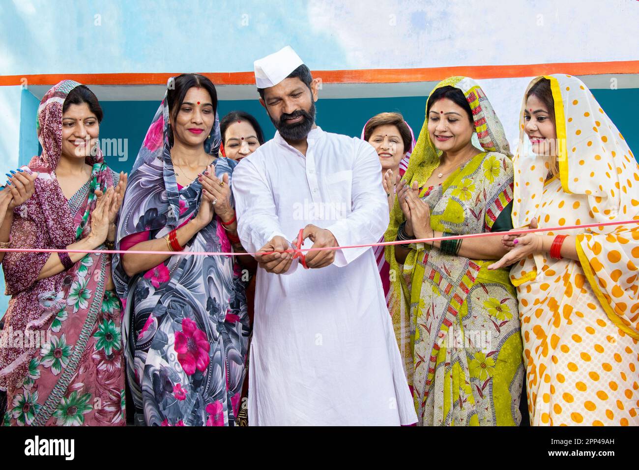 Indian man politician cutting red ribbon while group of traditional ...