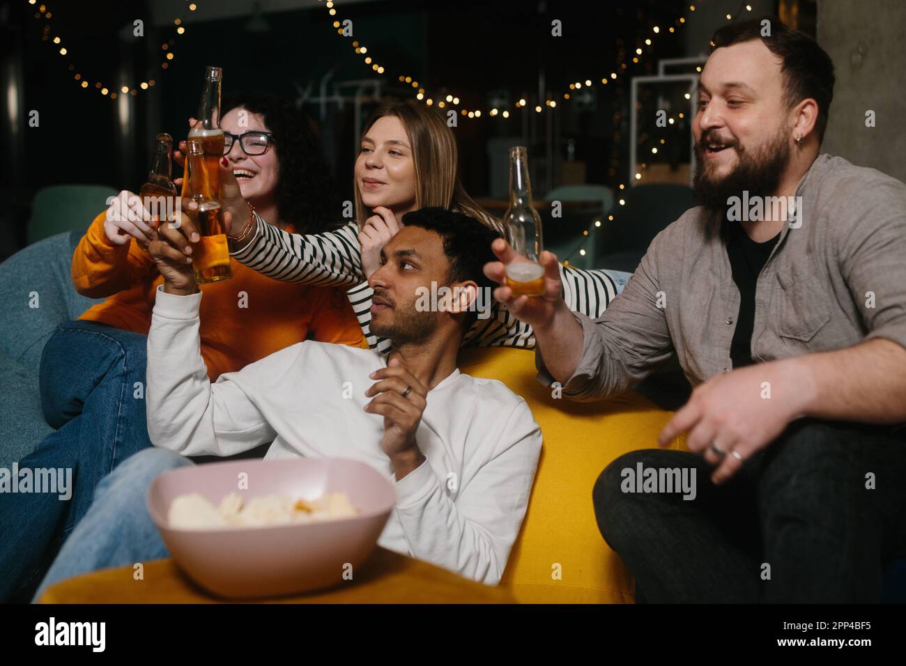 A group of friends eat snacks and drink beer while watching TV Stock ...