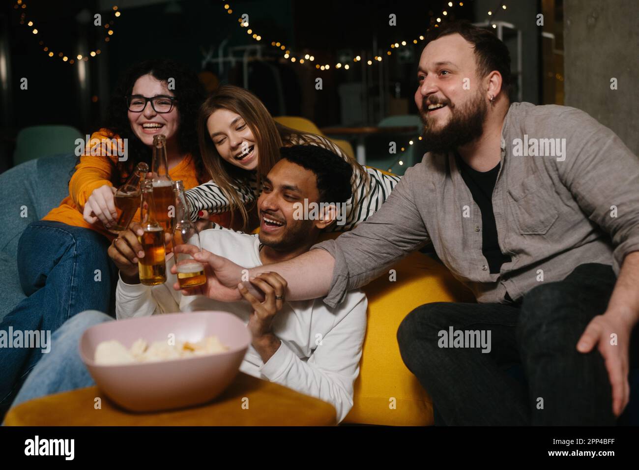 A group of friends eat snacks and drink beer while watching TV Stock ...