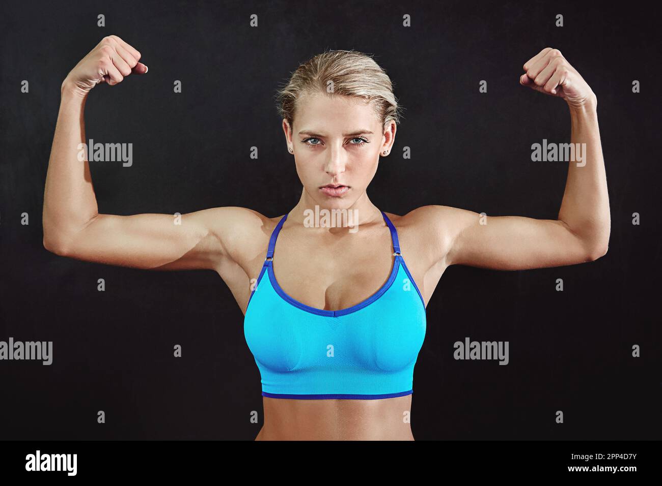 Woman of steel. Portrait of a sporty young woman flexing her muscles ...