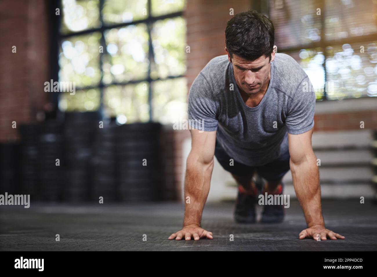 Hes a lean mean machine. a young man doing pushups in a gym Stock Photo ...