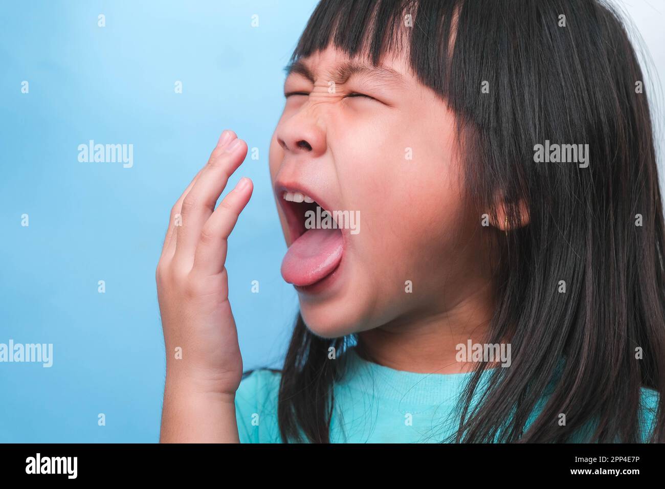 Little asian girl covering her mouth to smell the bad breath. Child ...
