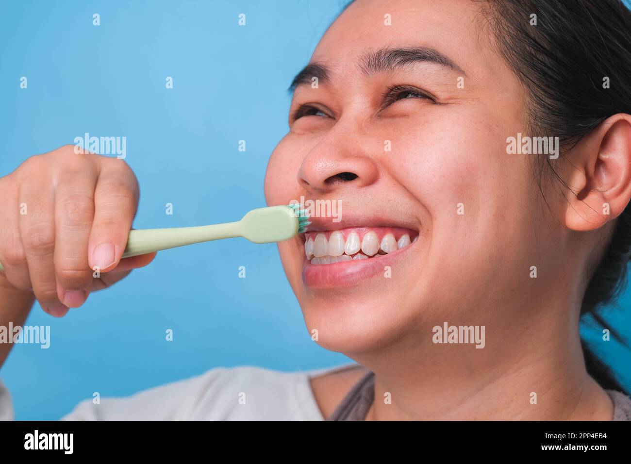 Happy Asian woman taking care of her teeth and holding a toothbrush ...
