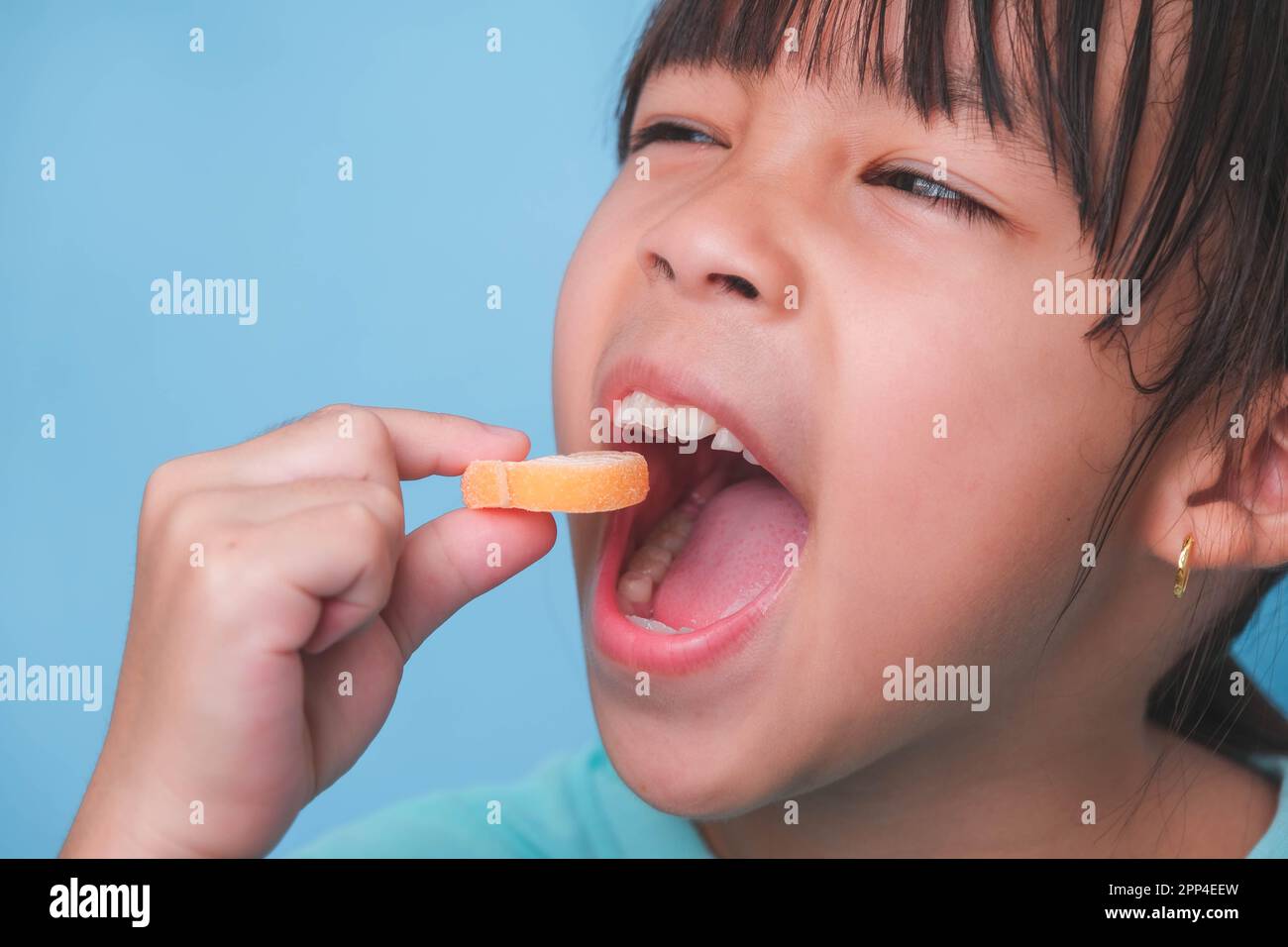 Smiling cute little girl eating sweet gelatin with sugar added isolated ...