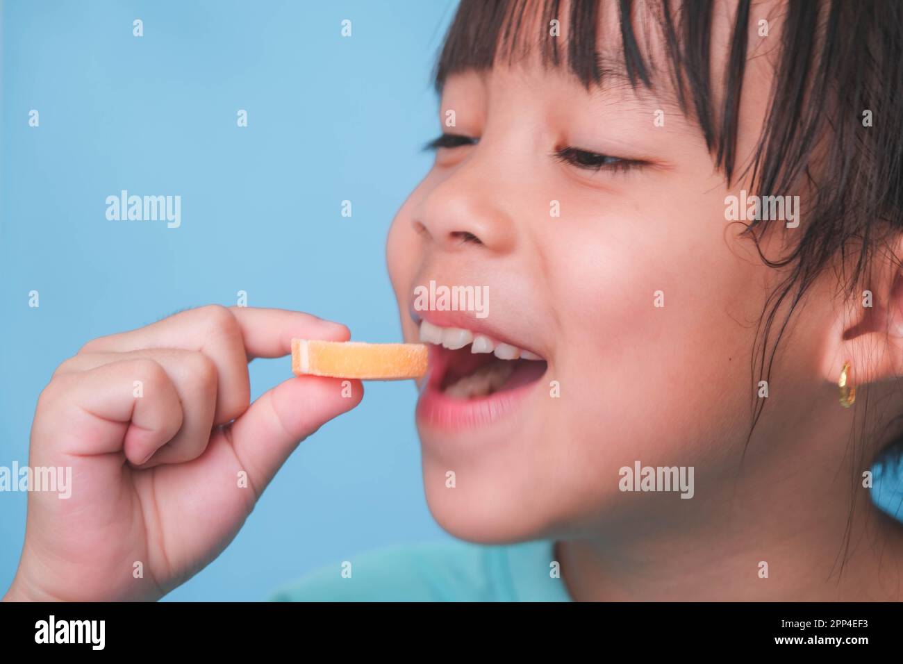 Smiling cute little girl eating sweet gelatin with sugar added isolated ...