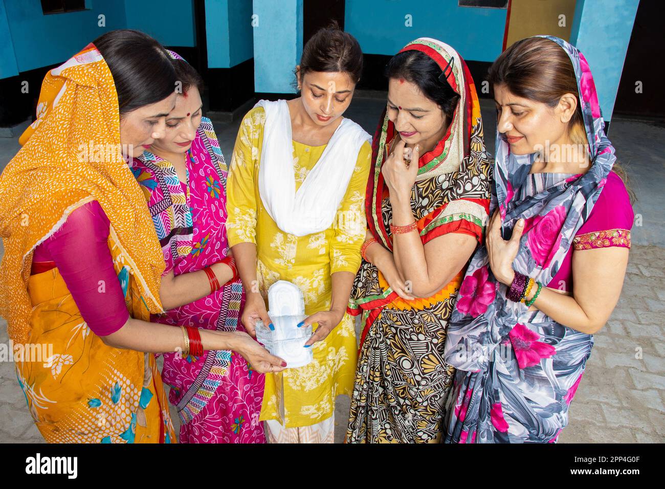 Young indian woman educating other traditional women about sanitary pad ...