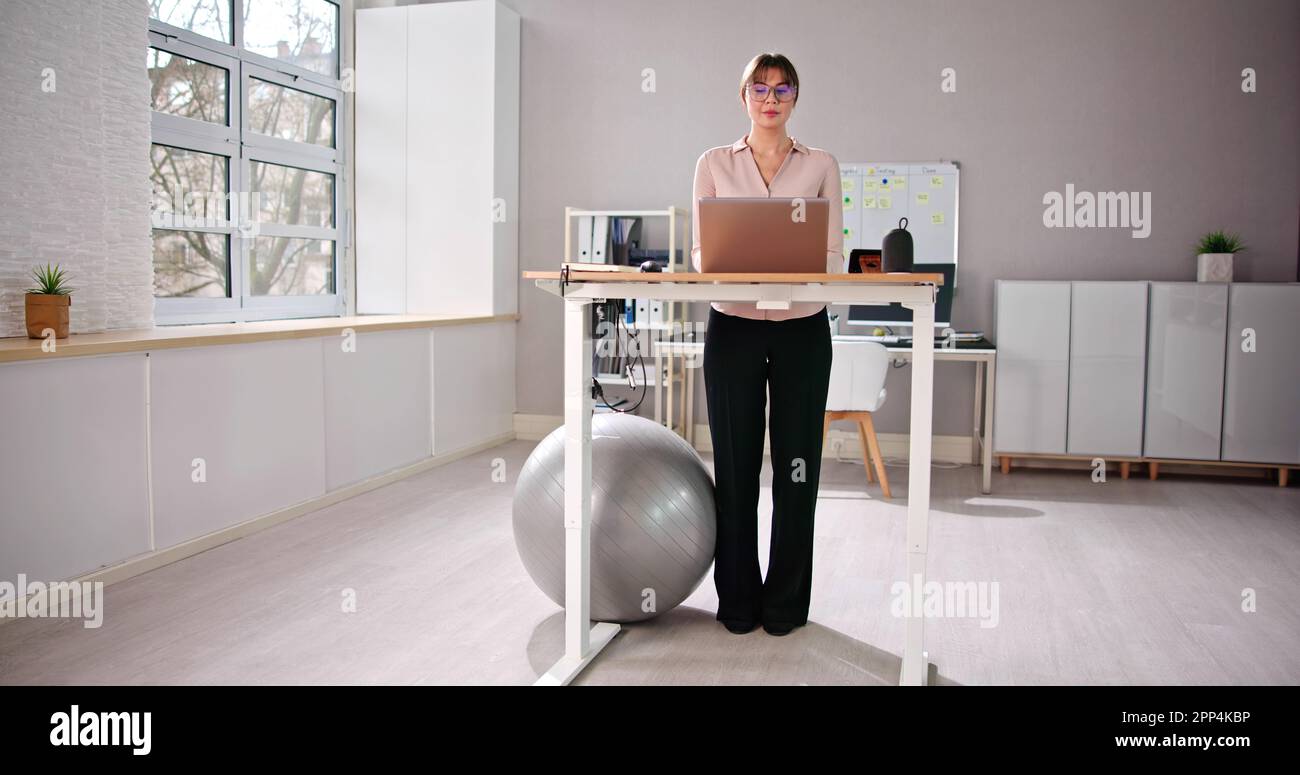 Woman Using Adjustable Height Standing Desk In Office For Good Posture ...