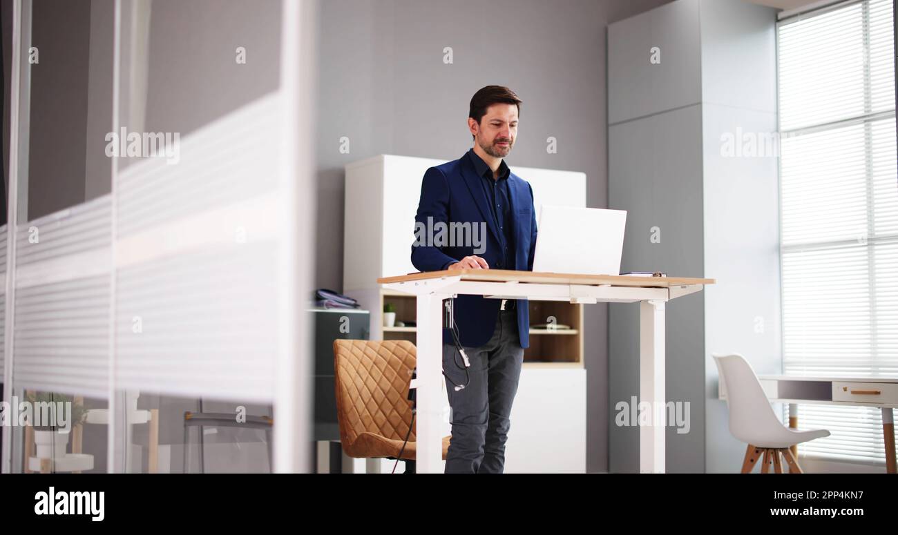 Adjustable Height Desk Stand In Office Using Computer Stock Photo - Alamy