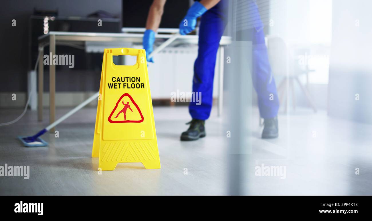 Low Section Of Male Janitor Cleaning Floor With Caution Wet Floor Sign ...