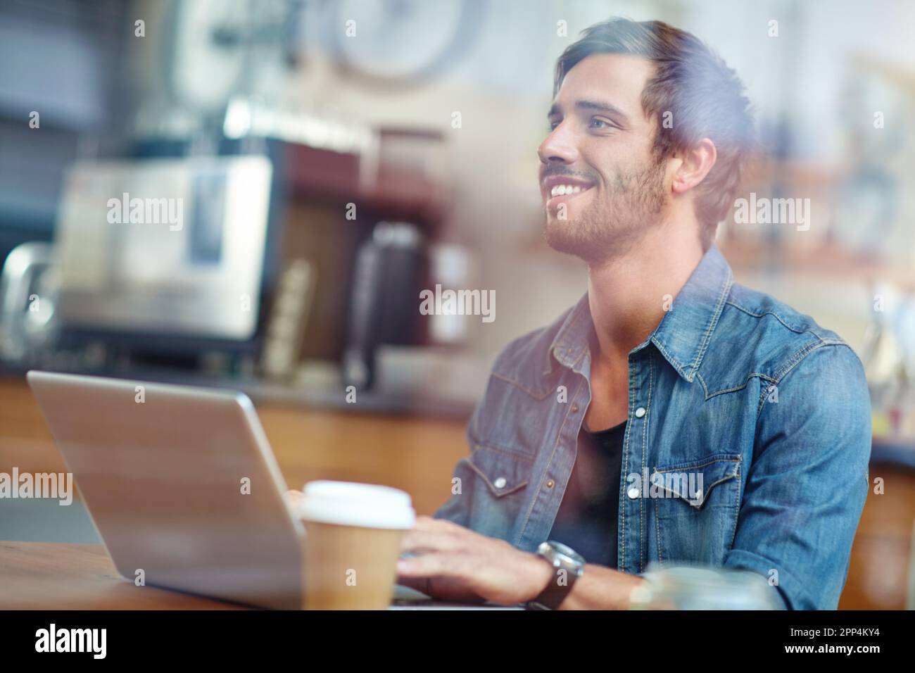 Coffee inspiration. a handsome young man sitting with his laptop in a ...