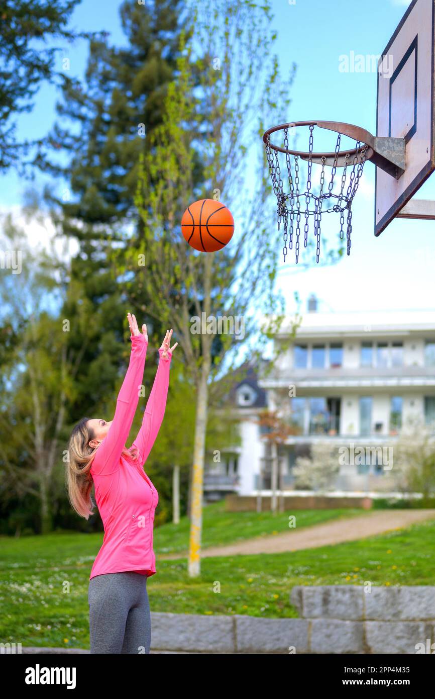Attractive blonde woman jumping and throwing baskets while playing ...