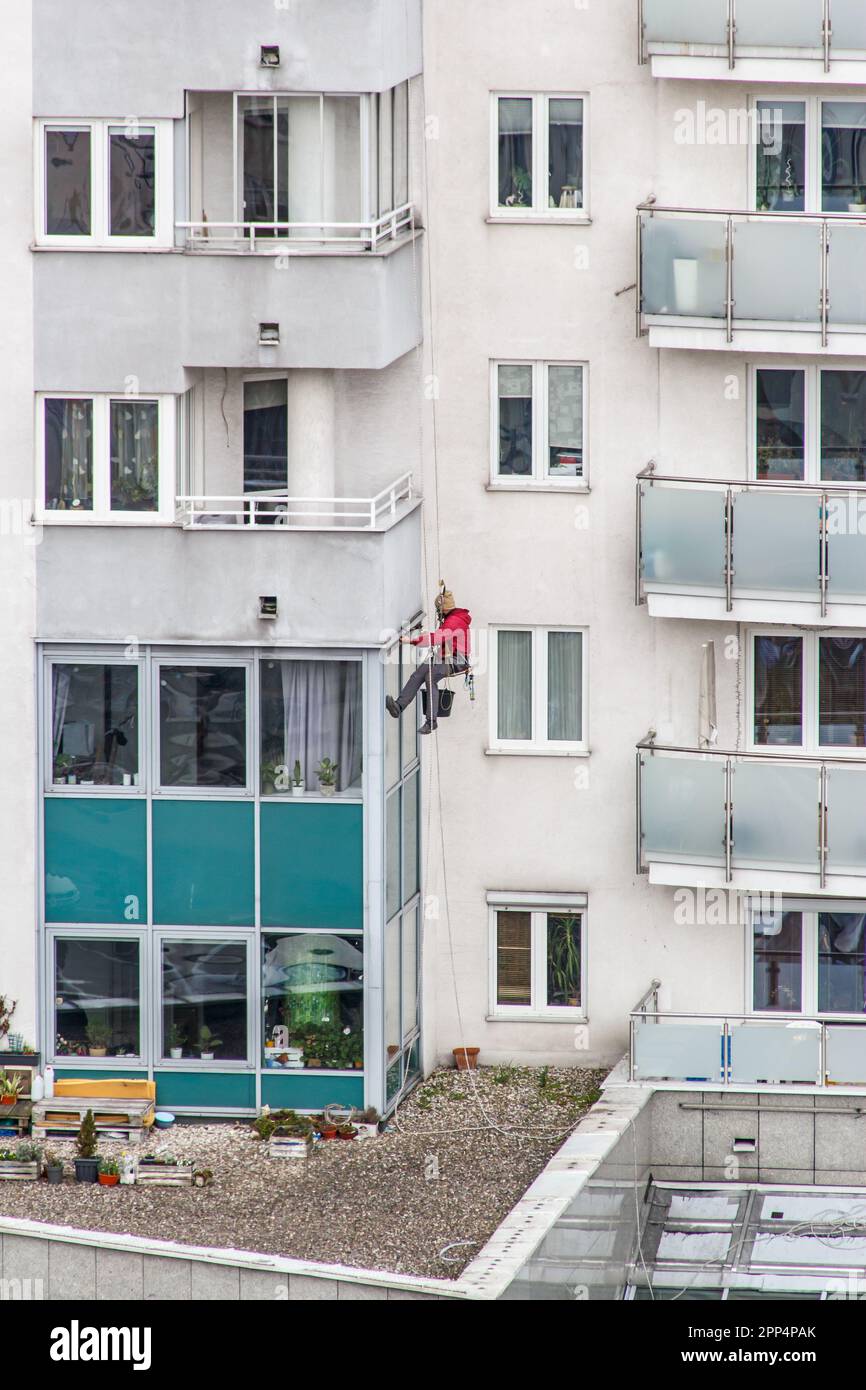 a man window cleaner suspended on ropes residental building working ...