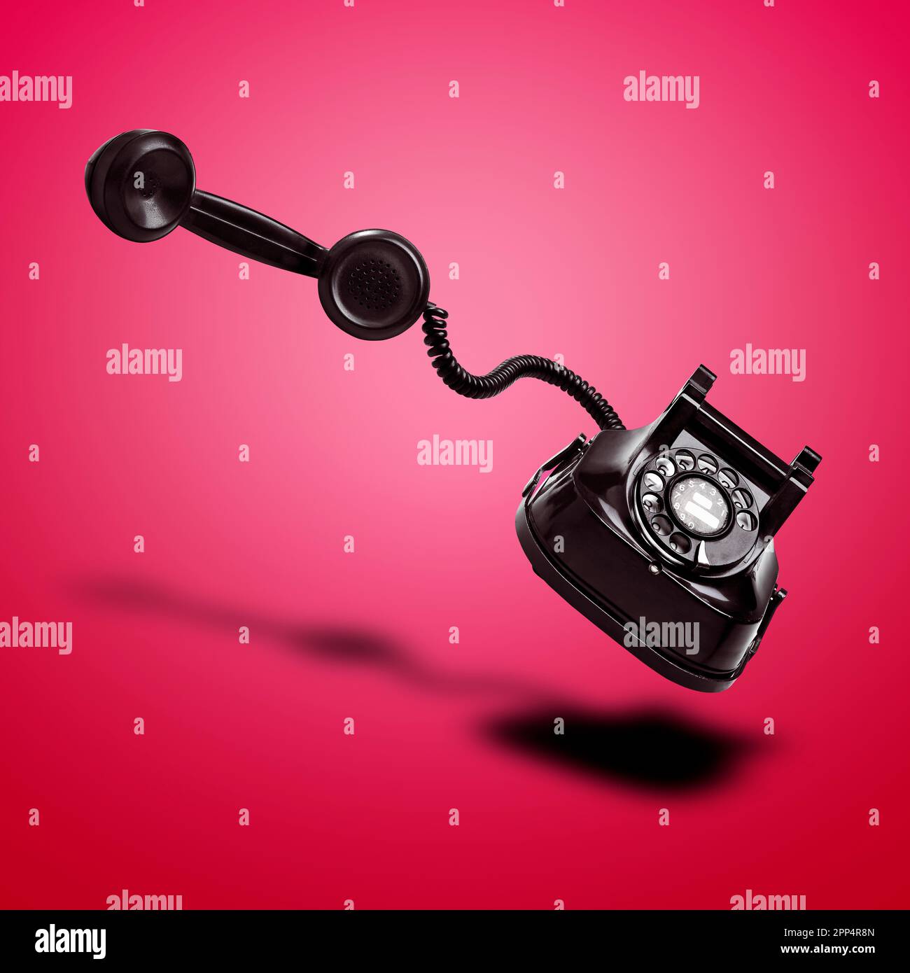 Floating Old black telephone with shadow against red radial gradient ...