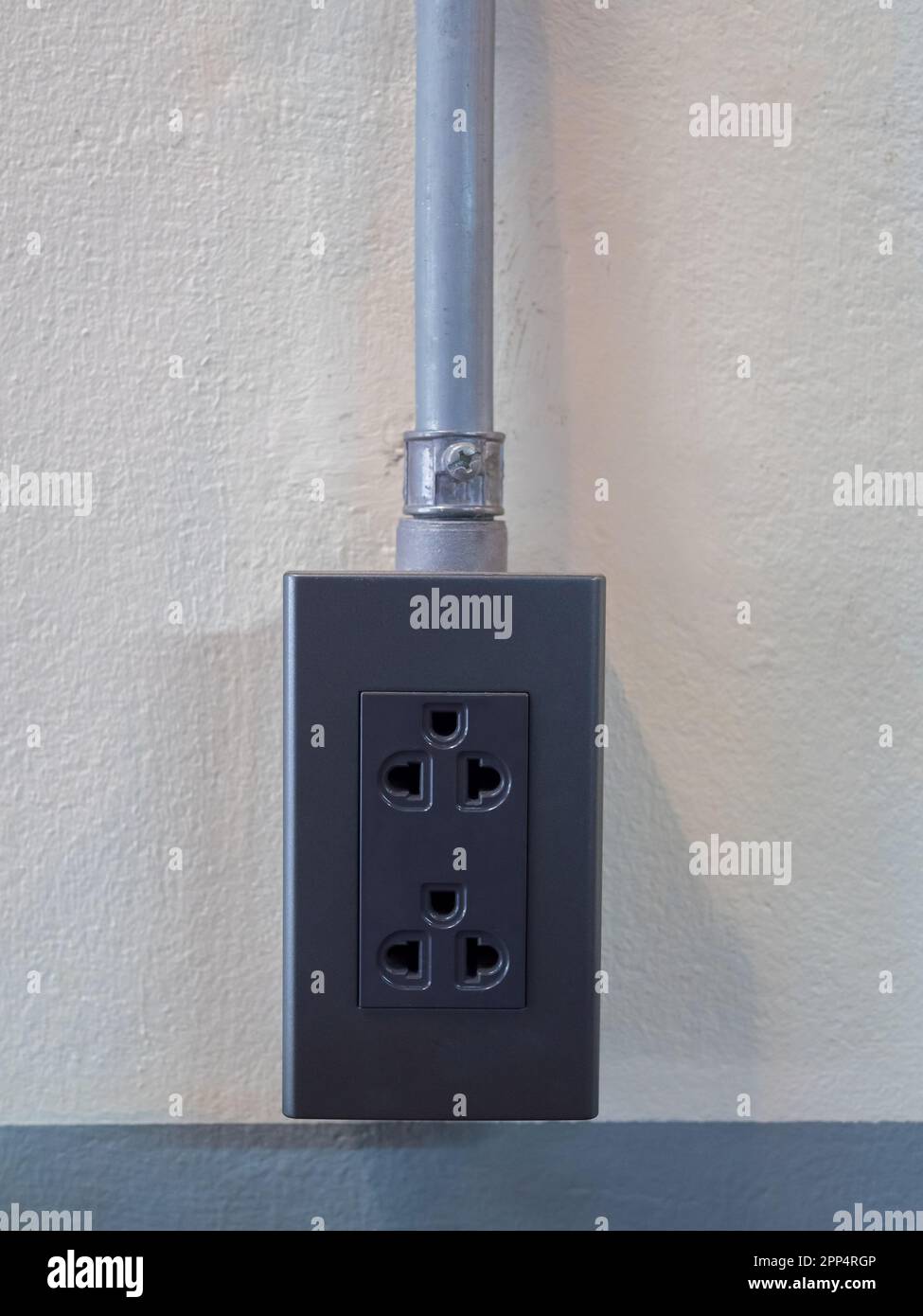 AC power socket, loft style and metal wire pipes on the concrete wall ...