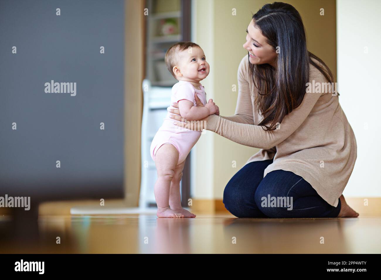 Mother helping baby stand hi-res stock photography and images - Alamy