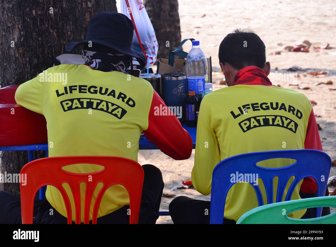 Two male lifeguards sit on the beach at Pattaya, Thailand, available if ...