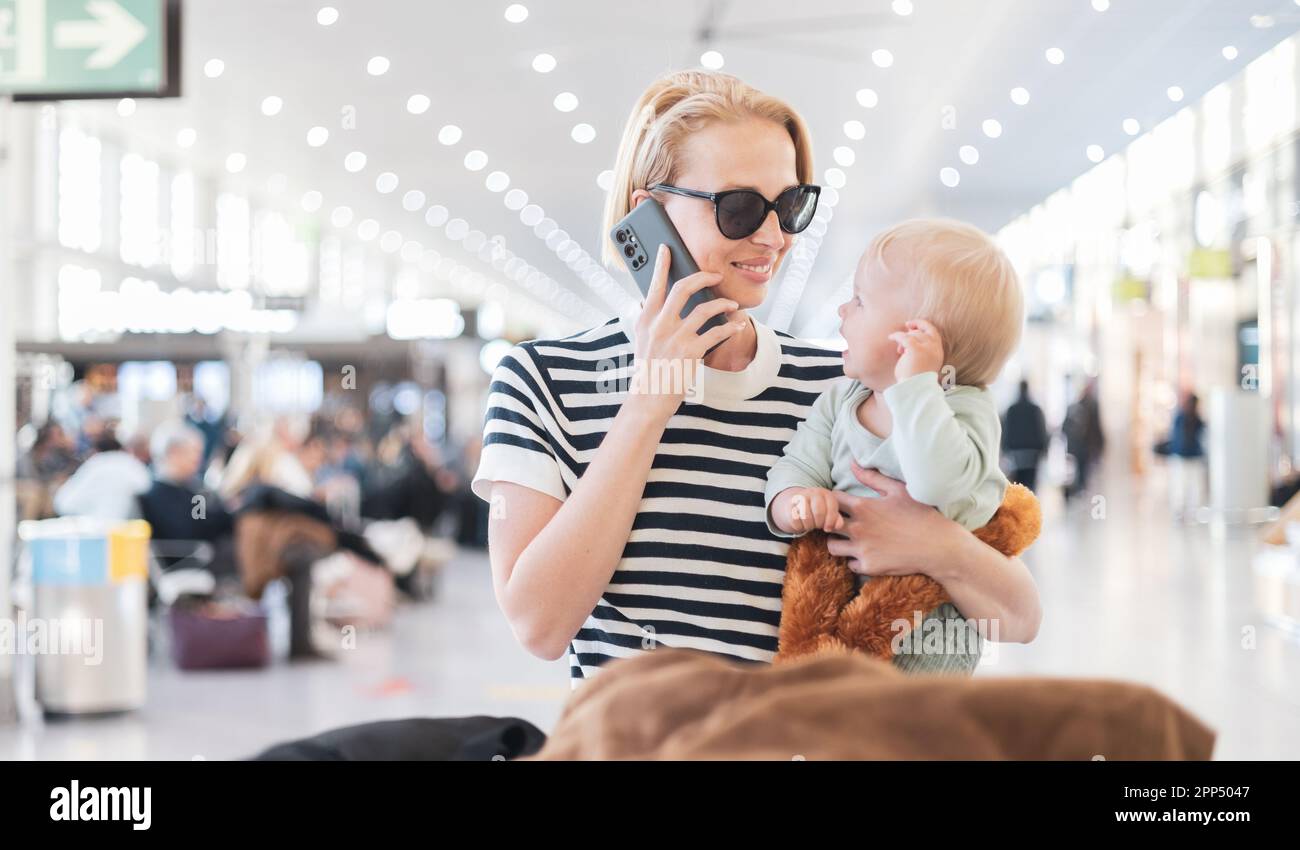 Mother talking on mobile phone while traveling with child, holding his ...